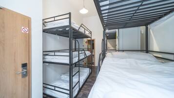 Um quarto de dormitório com beliches, porta de madeira e ventilador de teto.