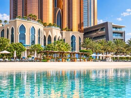 Um hotel na praia com piscina, palmeiras e arquitetura moderna.