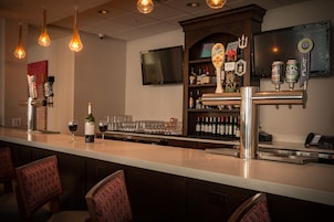 Uma área de bar com um balcão comprido, várias torneiras, copos e garrafas.