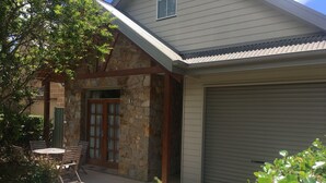 Uma casa com fachada de pedra, porta de garagem e um pátio com mesa e cadeiras.