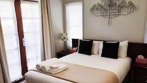 Quarto de hotel com uma cama grande, uma mesa de cabeceira, um abajur e um objeto decorativo na parede.