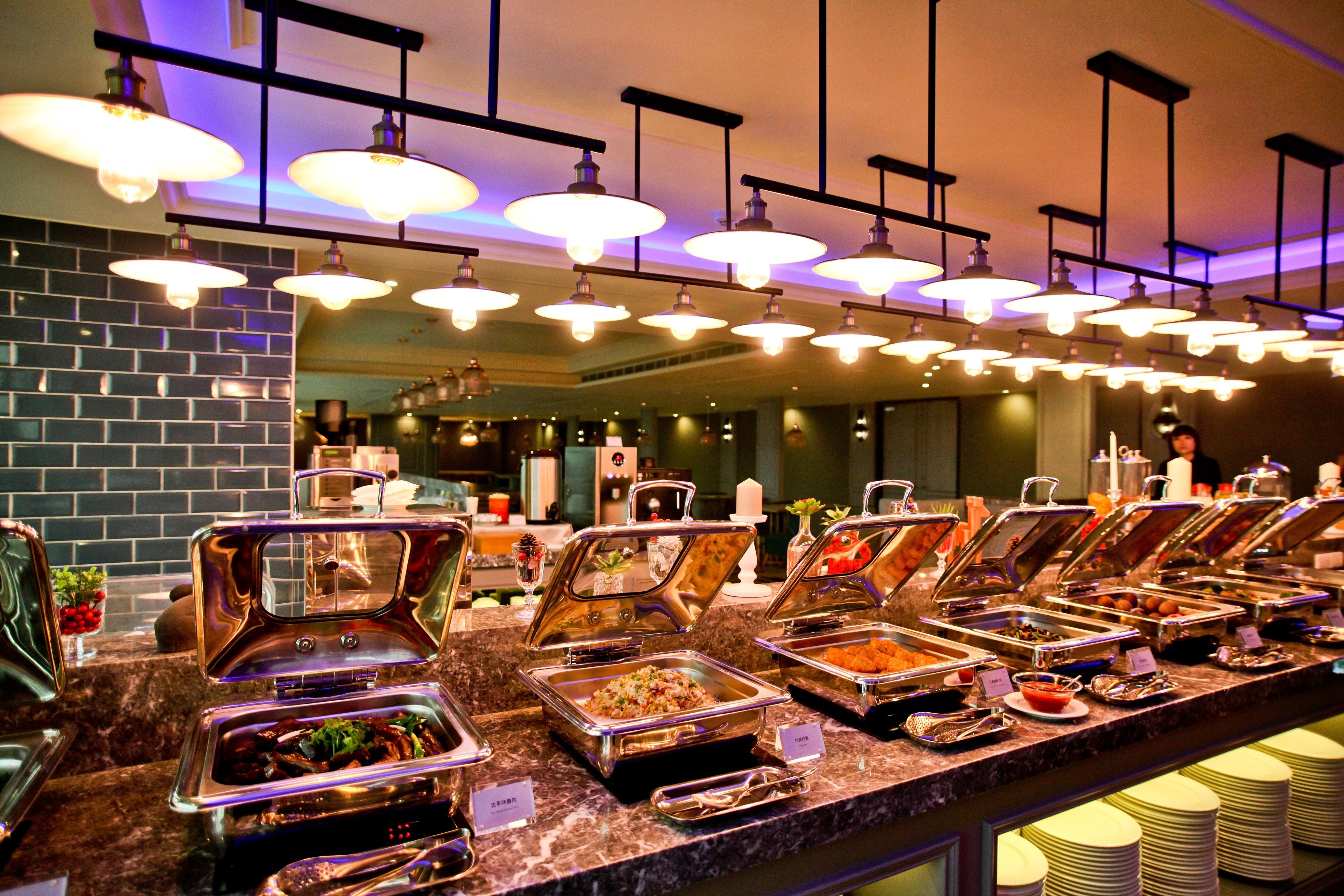 Buffet com várias estações de comida, cada uma com um refritório coberto.
