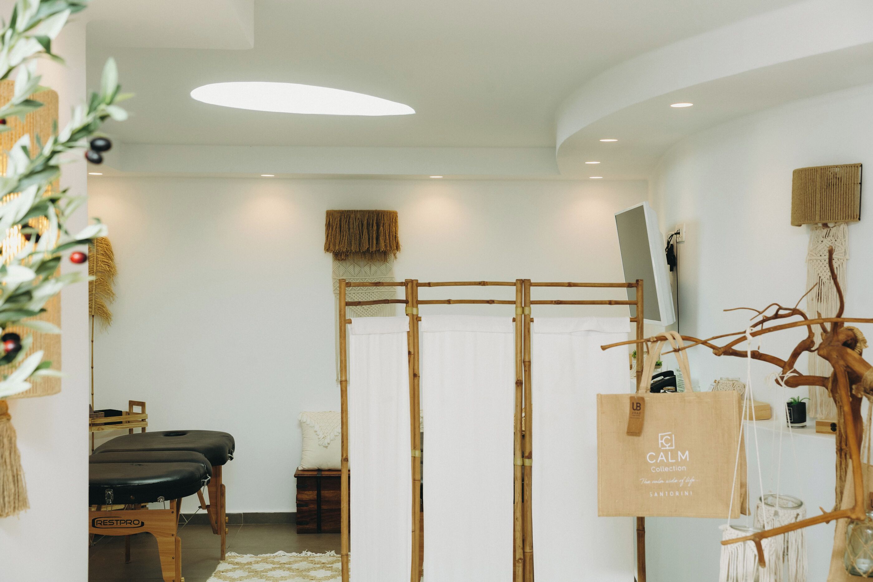 Um espaço de spa com um banco de madeira, um divisório de bambu e uma mala 'CALM Collection'.