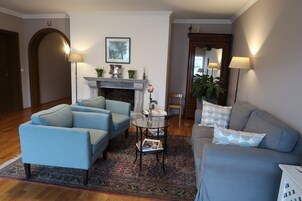 Uma sala de estar com lareira, dois sofás, uma mesa de centro e um tapete estampado.