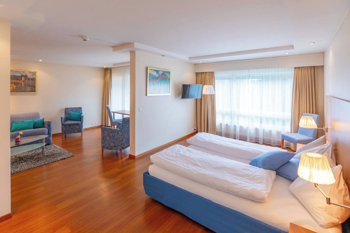 Quarto de hotel com uma cama grande, um sofá, uma cadeira e uma televisão.