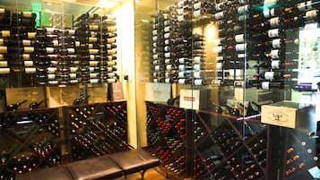 Uma adega com várias estantes de vinho e um banco.
