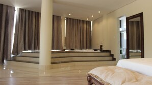 Quarto de hotel espaçoso com uma cama grande, área de estar com vista para o exterior e banheiro com banheira.