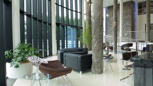 Um lobby moderno com balcão de atendimento, área de estar e amplas janelas.