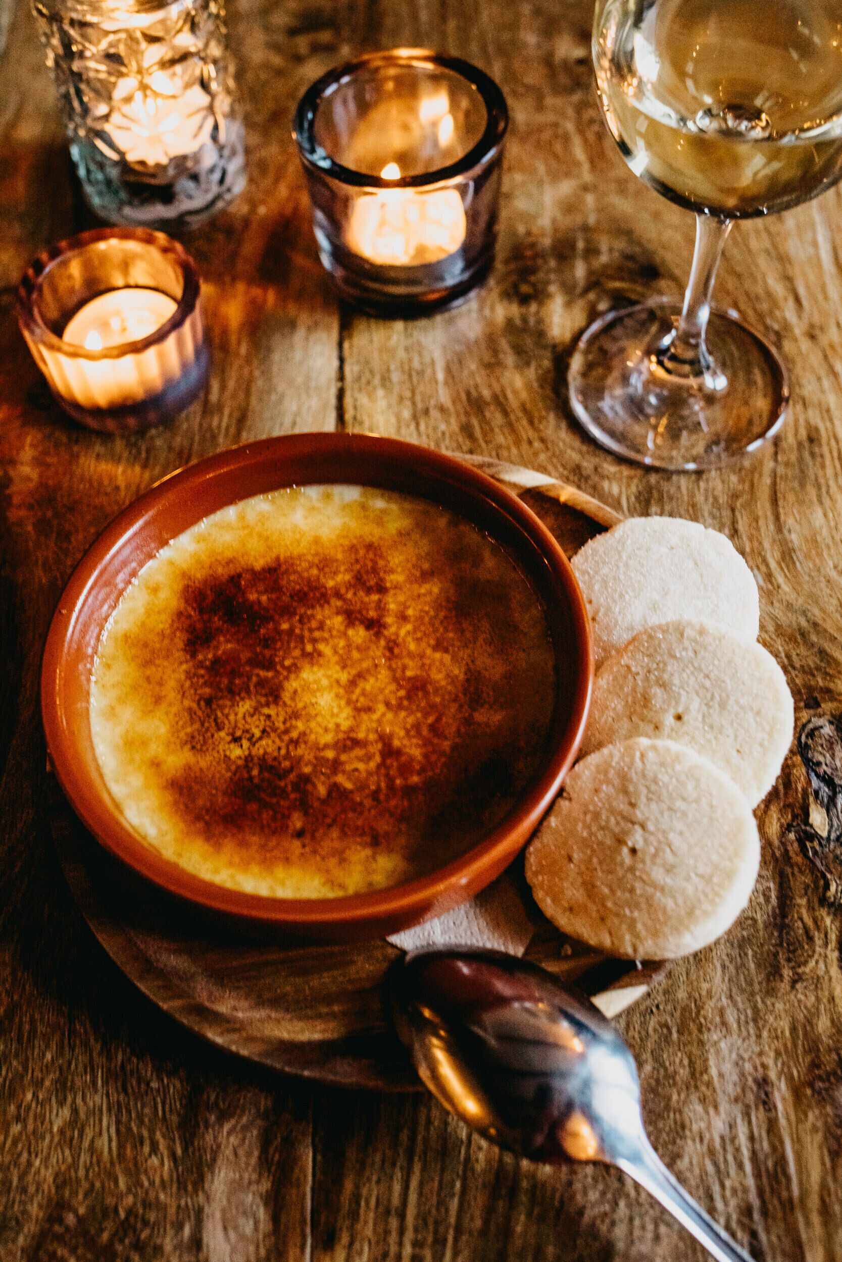 Uma sobremesa com cobertura caramelizada, acompanhada de vários pequenos bolos redondos em uma mesa de madeira.