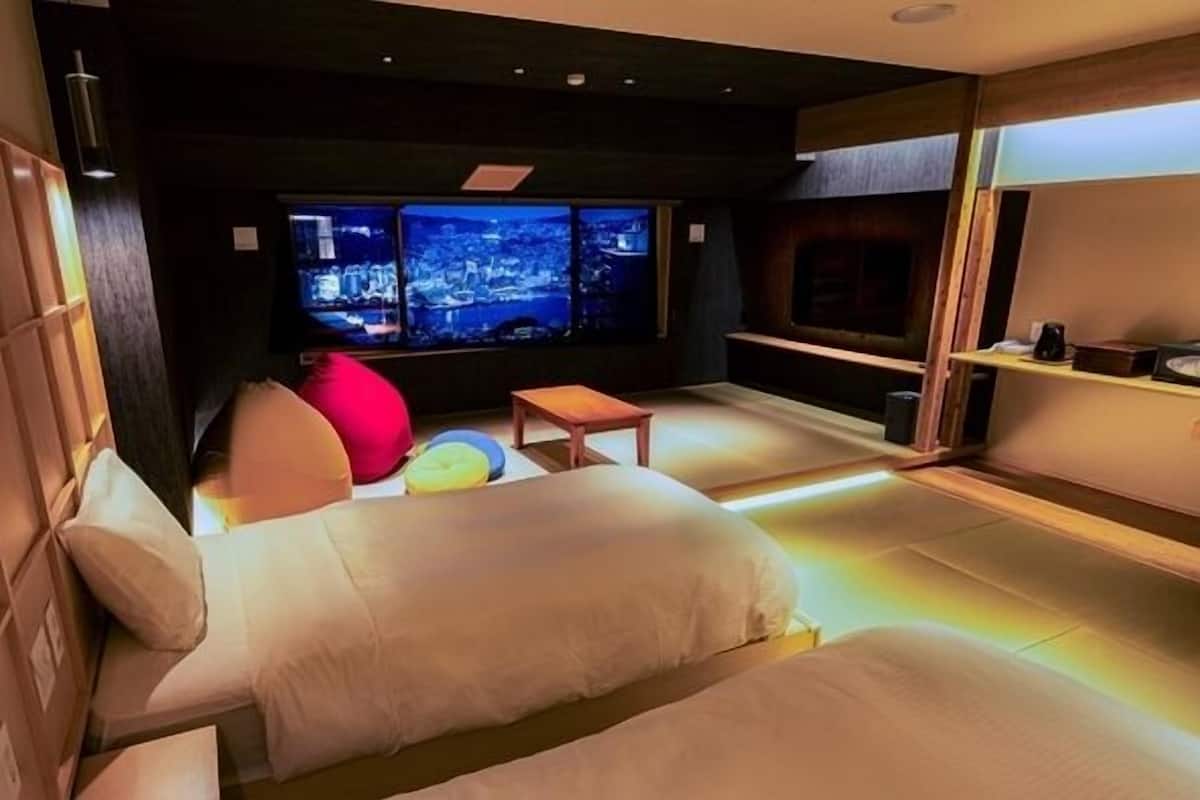 Quarto moderno com sofá, uma mesinha e TV exibindo uma vista urbana.