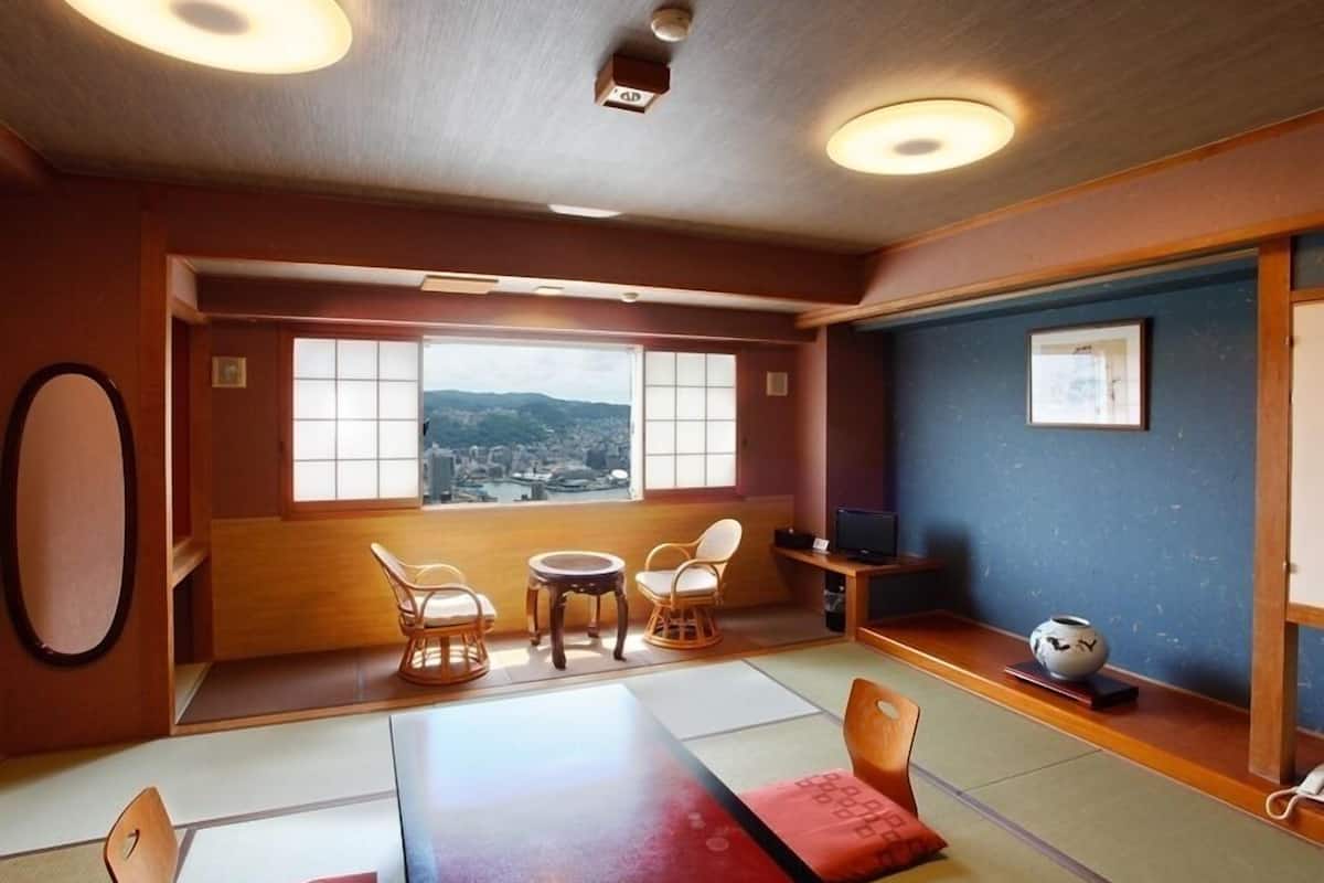 Um quarto japonês tradicional com tatames, uma mesa baixa e cadeiras.