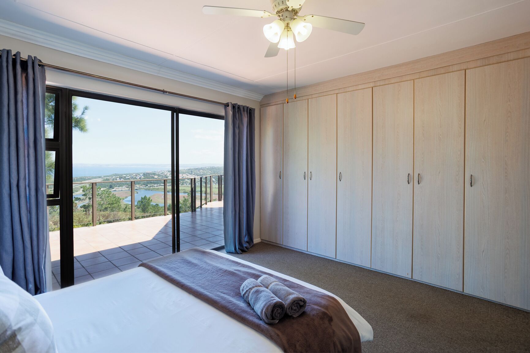 Um quarto com cama, um guarda-roupa espaçoso e uma varanda com vista.
