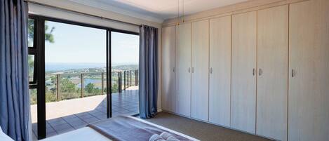 Um quarto com cama, um guarda-roupa espaçoso e uma varanda com vista.