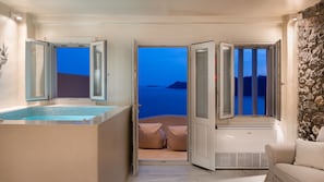 Quarto com banheira, sofá e vista para o mar.