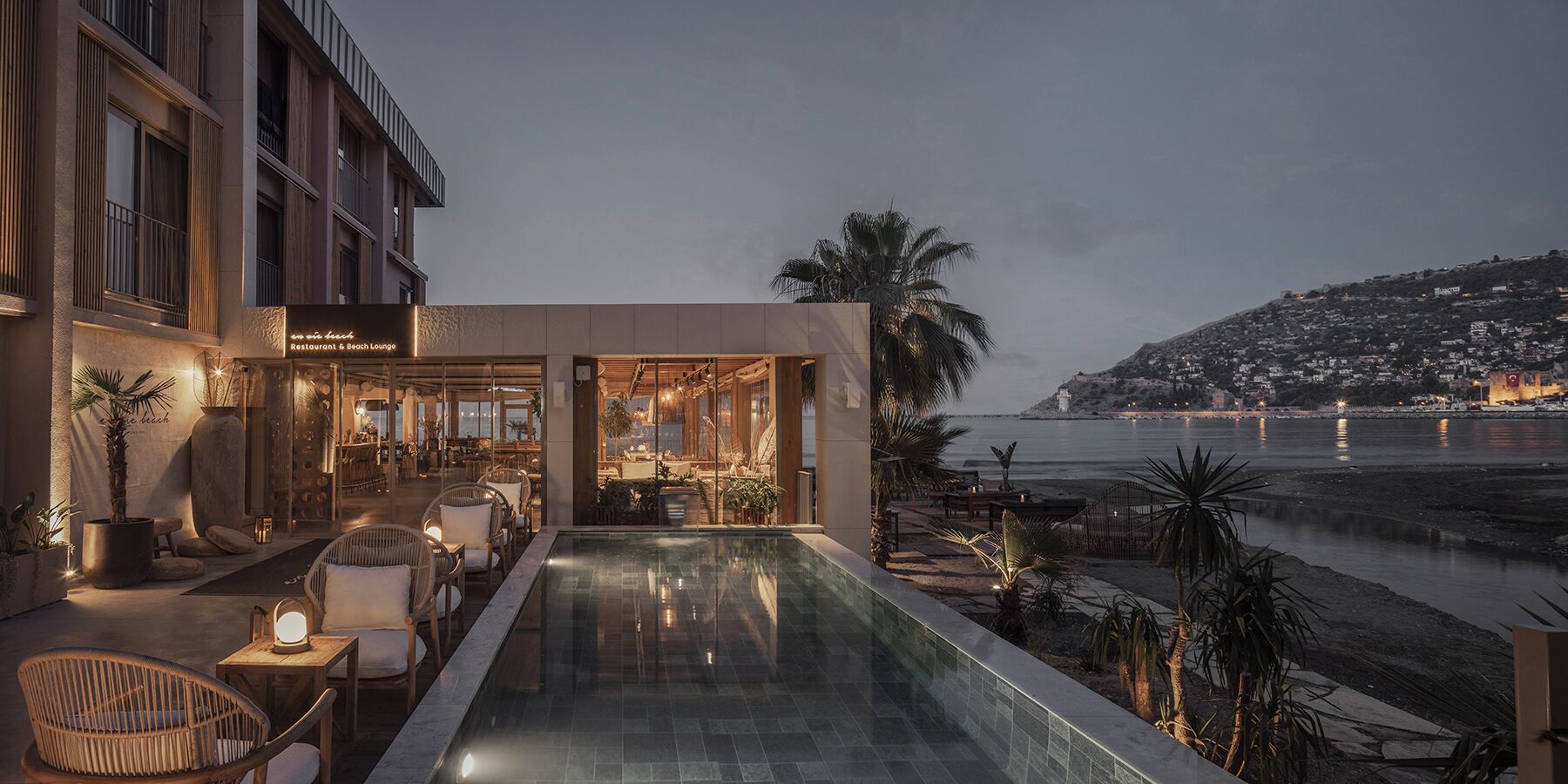 Piscina no terraço com restaurante e área de estar, com vista para a paisagem costeira.