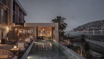 Piscina no terraço com restaurante e área de estar, com vista para a paisagem costeira.