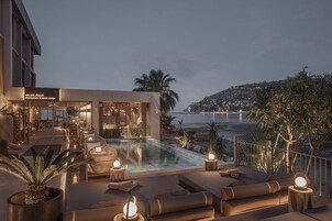 Uma área de piscina no terraço com assentos de lounge, um restaurante e vista para o oceano.