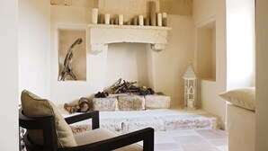 Um quarto acolhedor com lareira, um banquinho e um candeeiro.