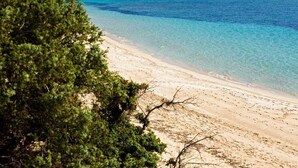 Uma praia com águas turquesa cristalinas e uma faixa de areia, rodeada por vegetação verde.