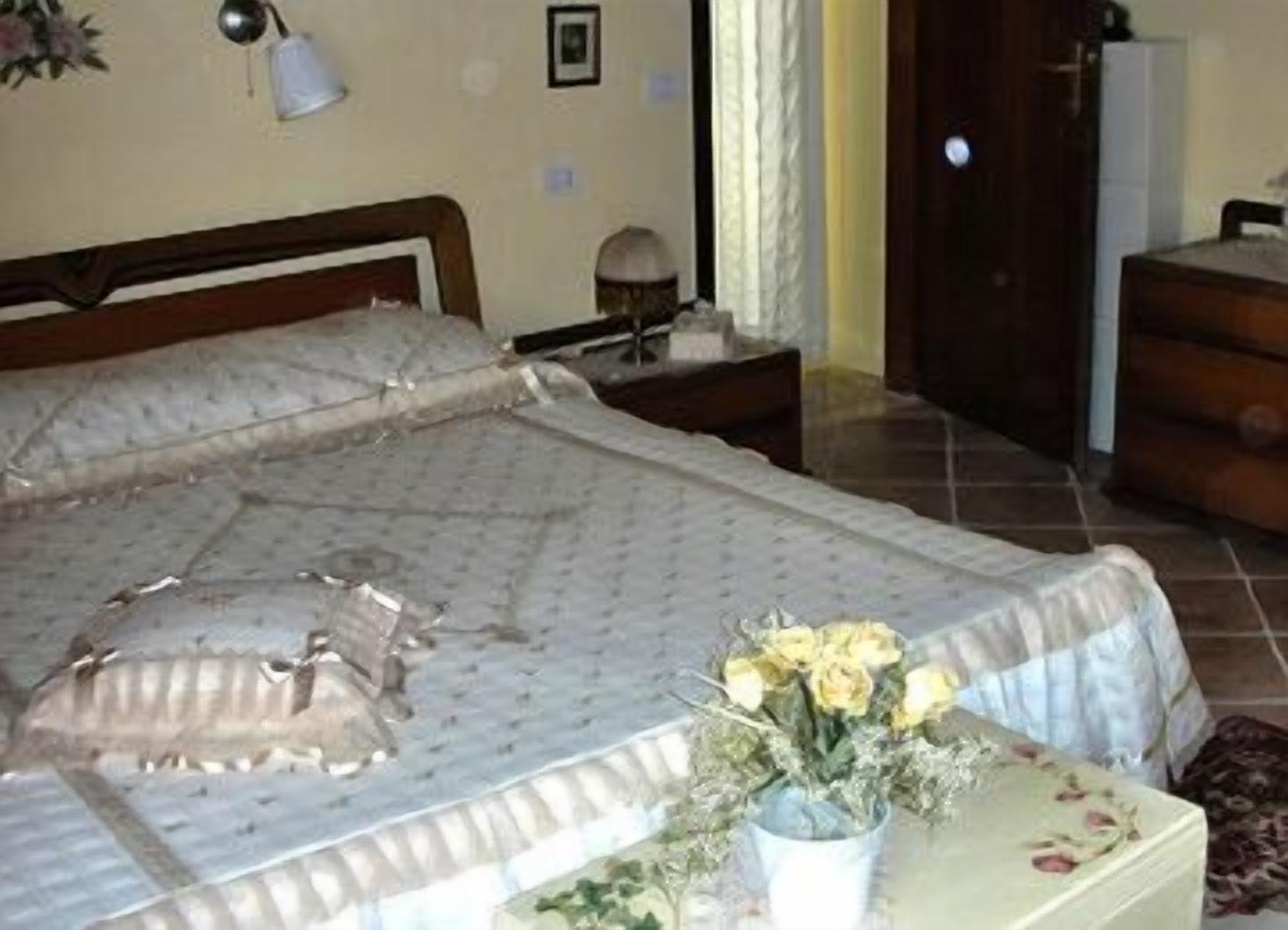 Quarto com cama, mesa de cabeceira e cômoda.