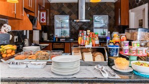 Um buffet de café da manhã com diversos alimentos, incluindo frutas, cereais e laticínios.