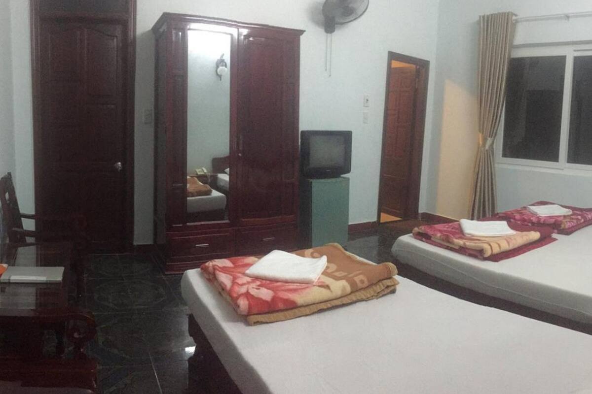 Quarto de hotel com duas camas, televisão, guarda-roupa e espelho.