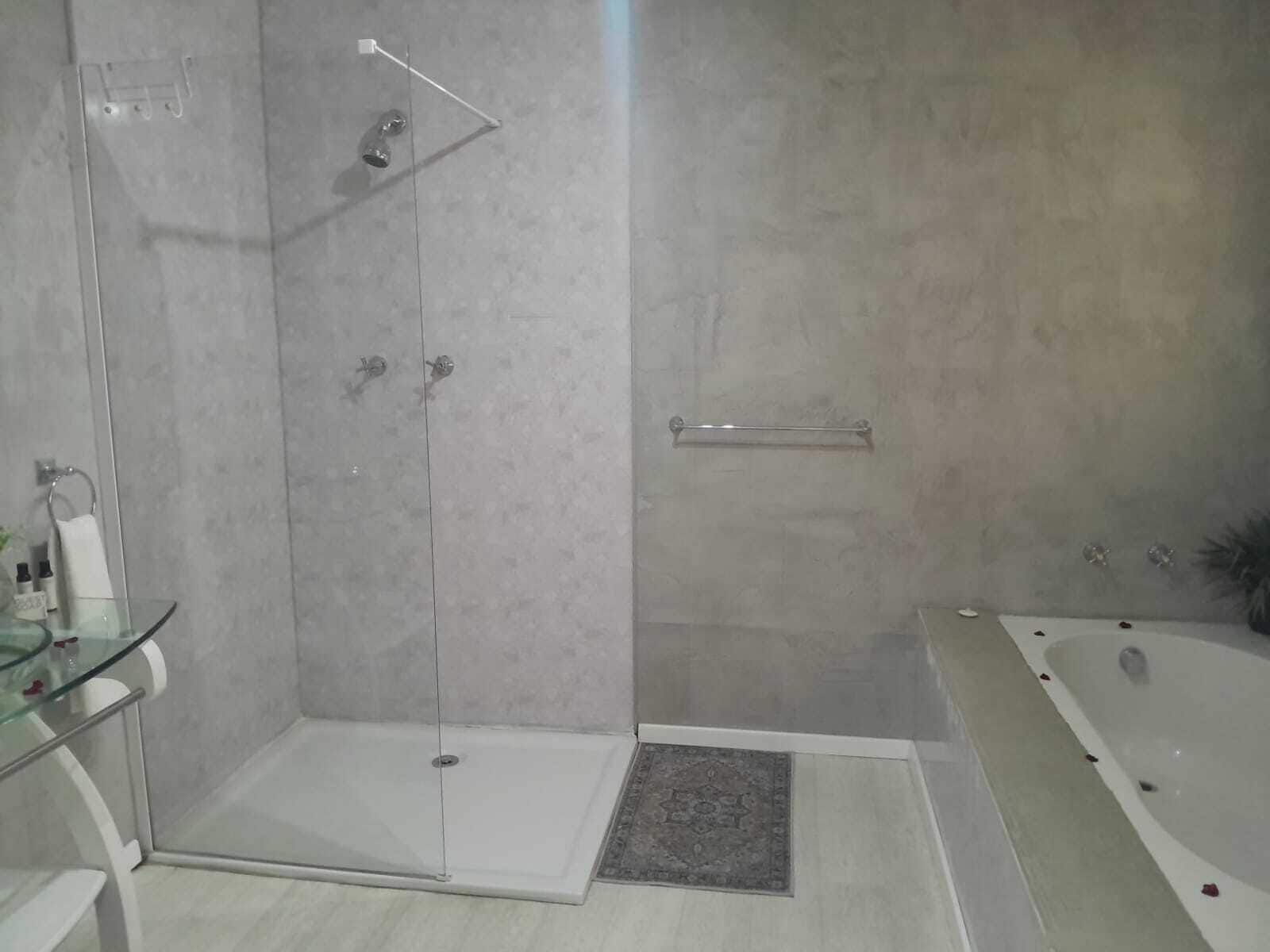 Um banheiro moderno com box de vidro, banheira e toucador de vidro.