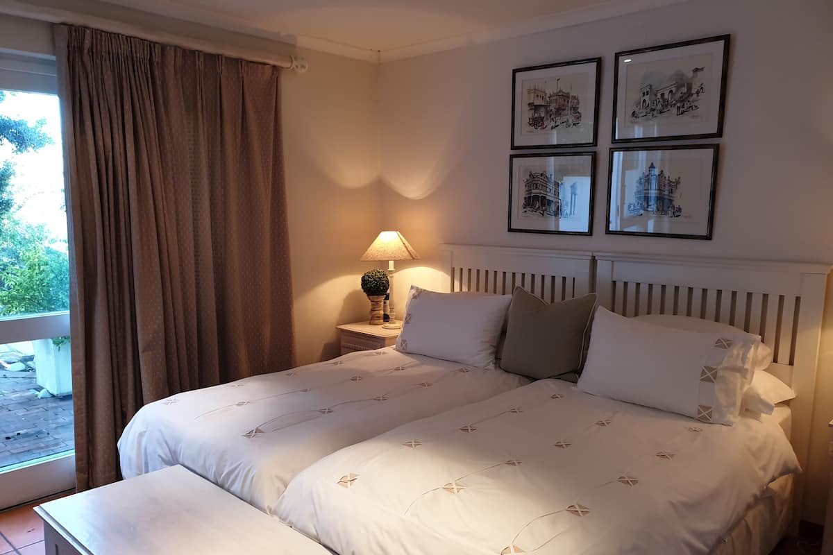 Um quarto bem arrumado com uma cama grande, uma mesa de cabeceira com abajur e uma janela com cortinas.