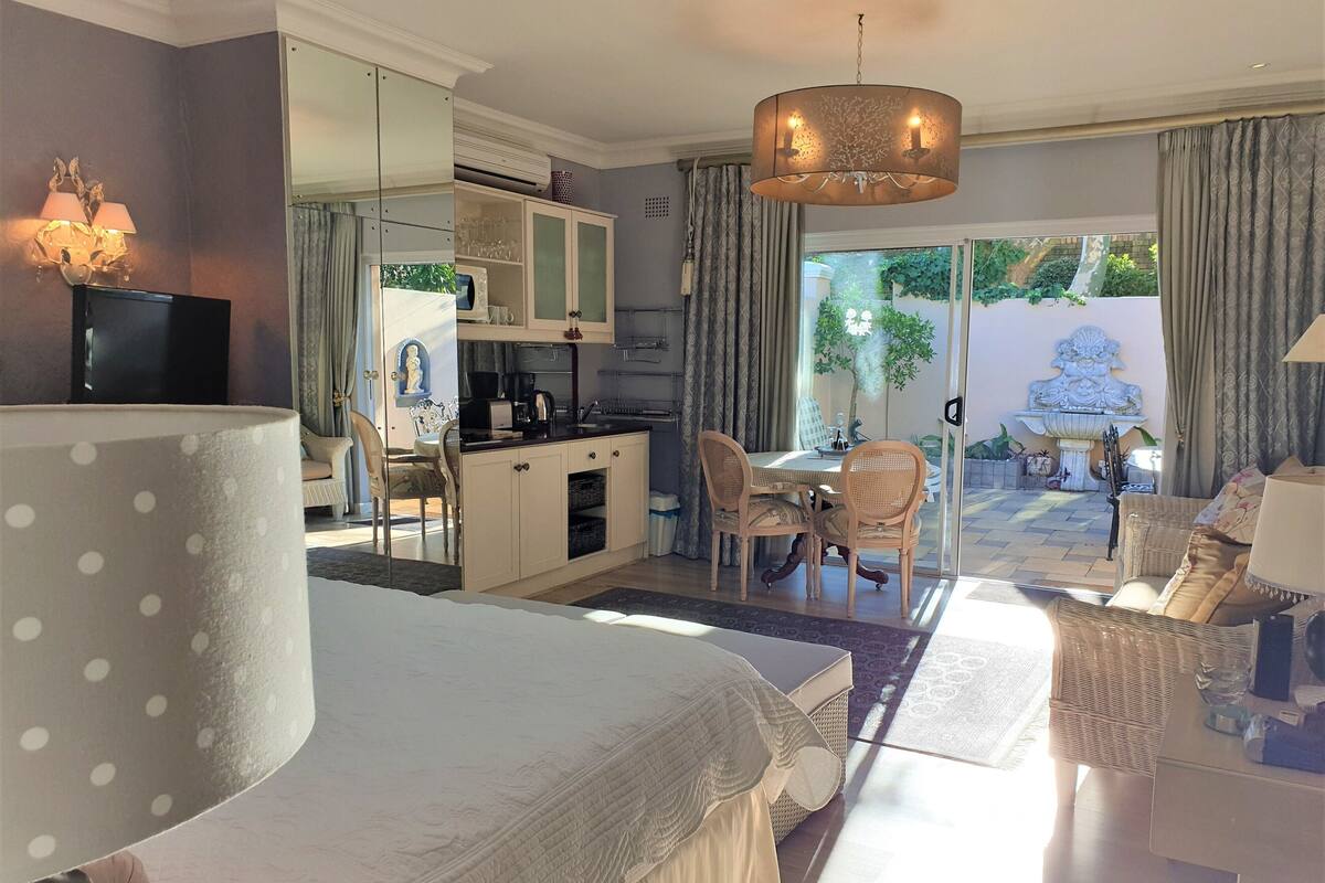 Quarto de hotel com cama, área de jantar, cozinha e vista para o exterior.