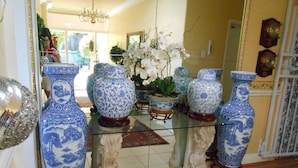 Quarto com mesa de centro de vidro rodeada por vasos estampados em azul e branco.