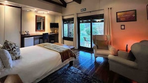 Quarto de hotel com cama, escrivaninha, cadeira e uma janela grande.