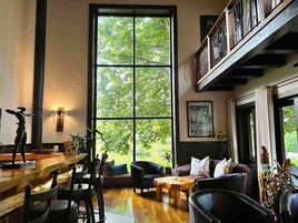 Um quarto amplo com uma grande janela, uma mesa de jantar de madeira e assentos confortáveis.