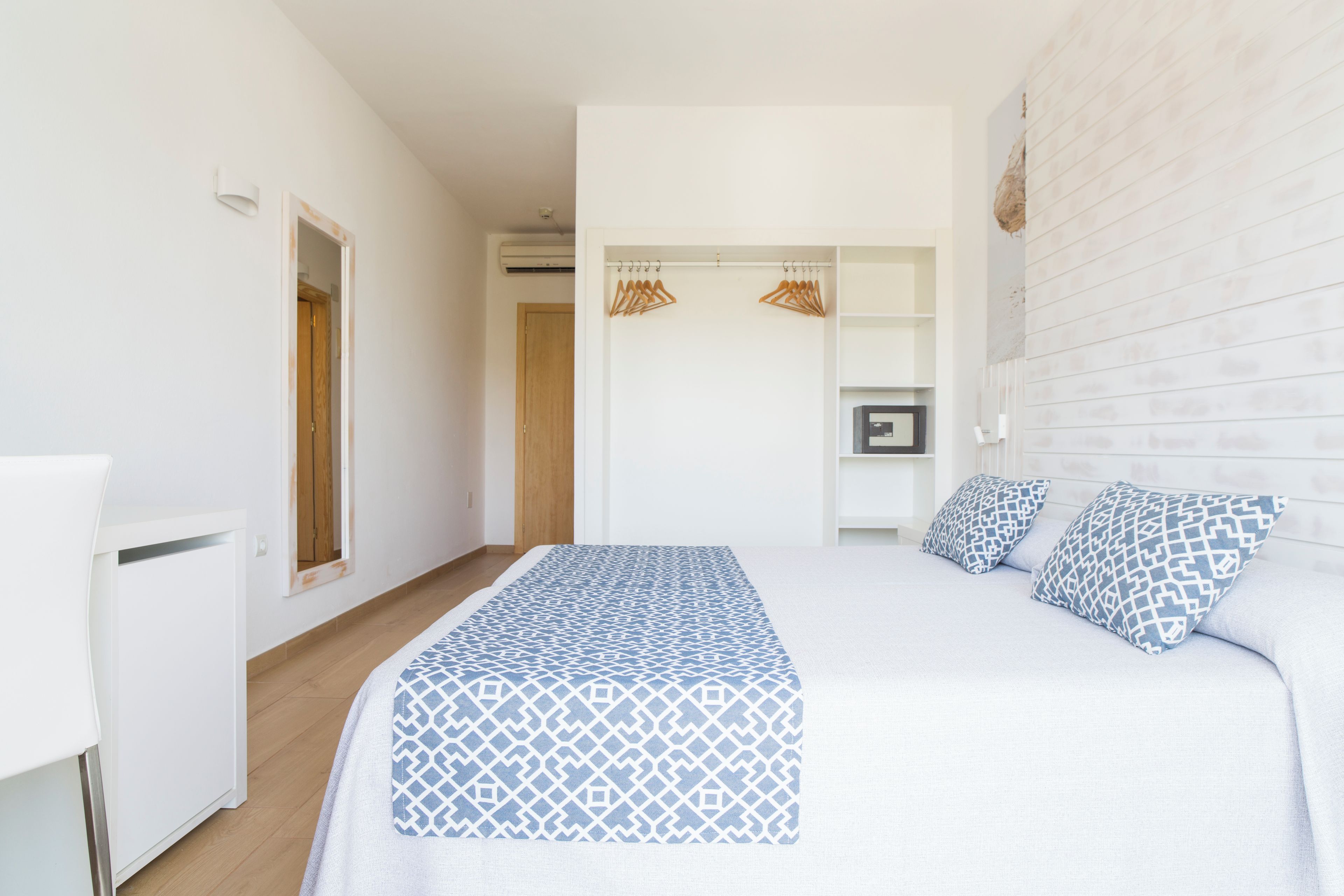 Quarto com cama, guarda-roupa e espelho.