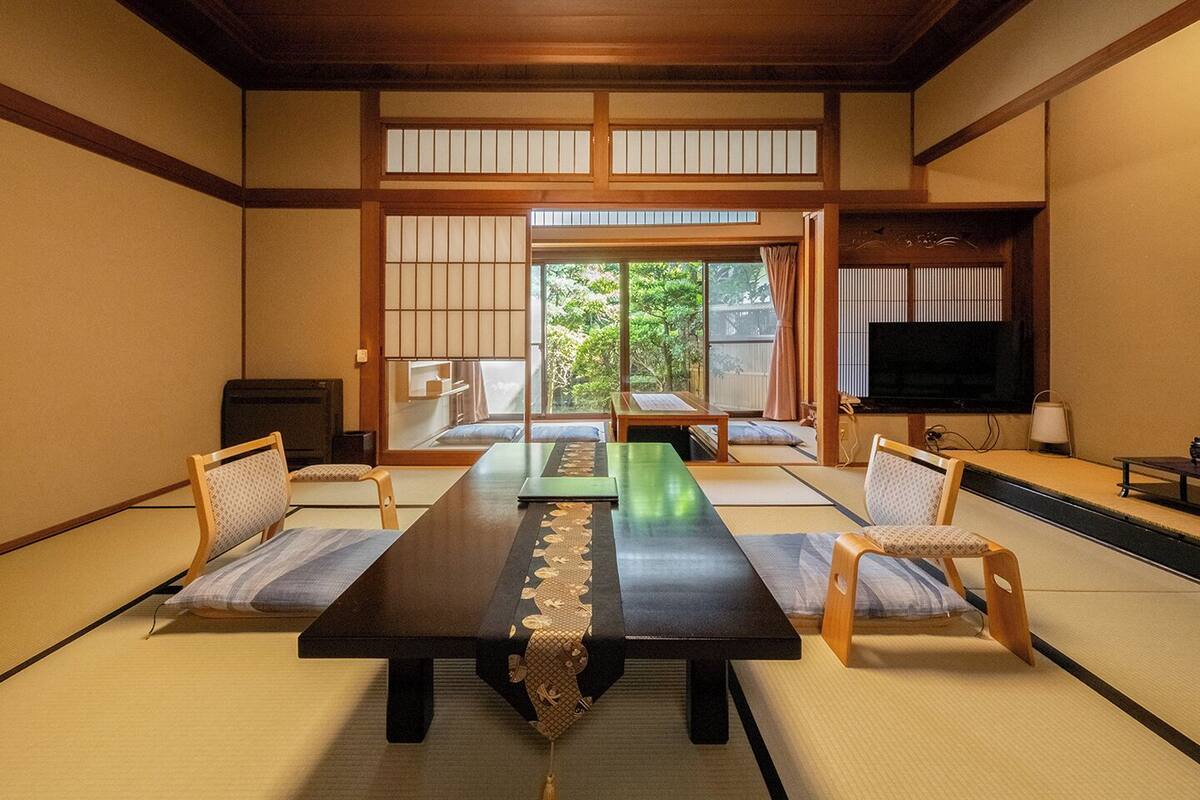 Um quarto japonês tradicional com tatames, uma mesa baixa e portas deslizantes.