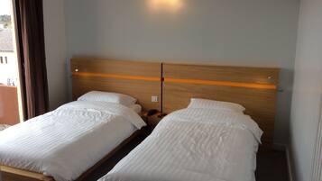 Uma cama de casal com cabeceira de madeira e mesa de cabeceira com abajur.