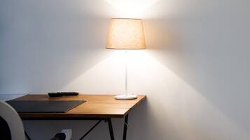 Uma mesa com uma luminária, um controle remoto e um tapete preto.