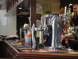 Um bar com várias torneiras de cerveja e um relógio na parede.