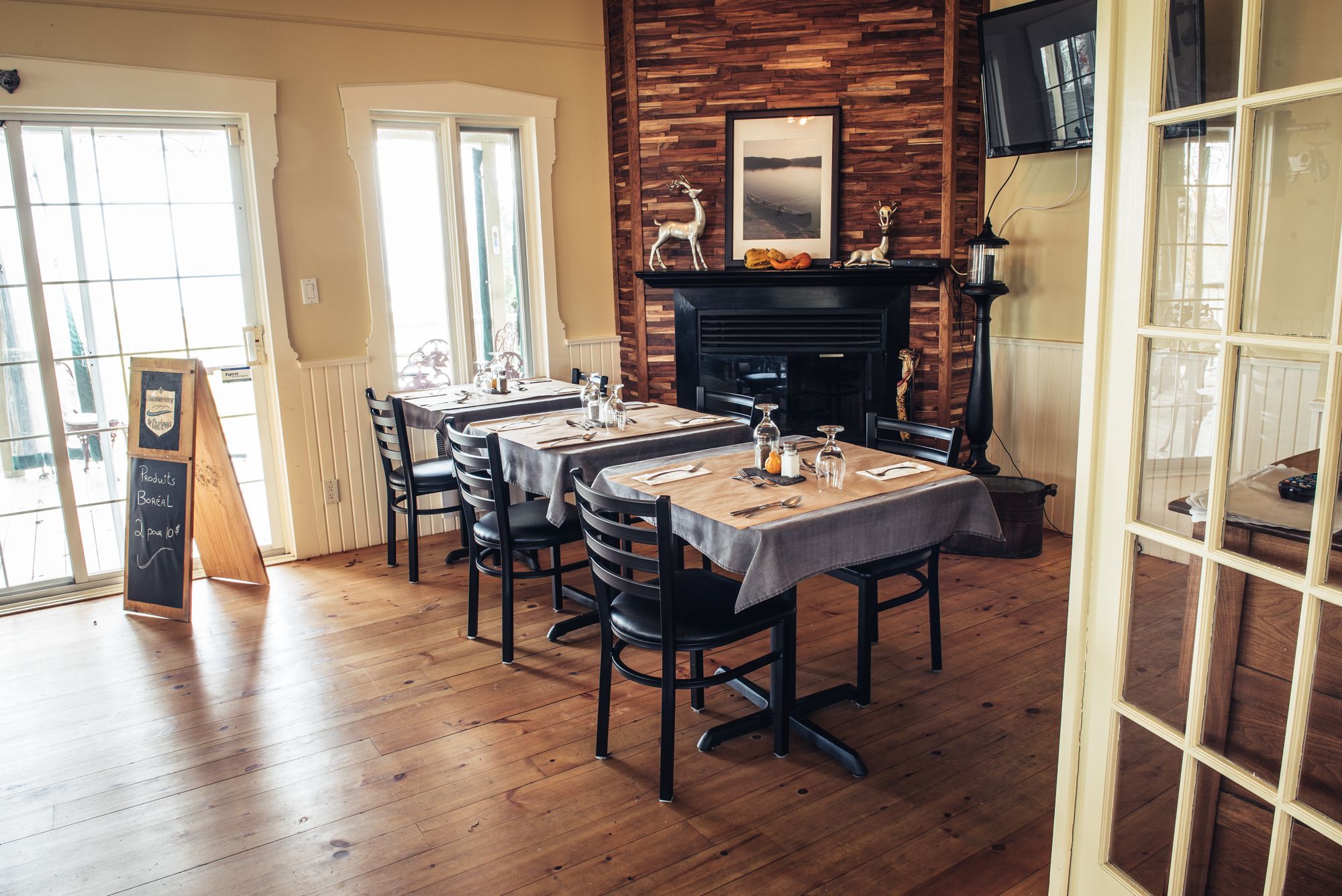 Uma sala de jantar com piso de madeira, lareira e mesa posta para quatro pessoas.