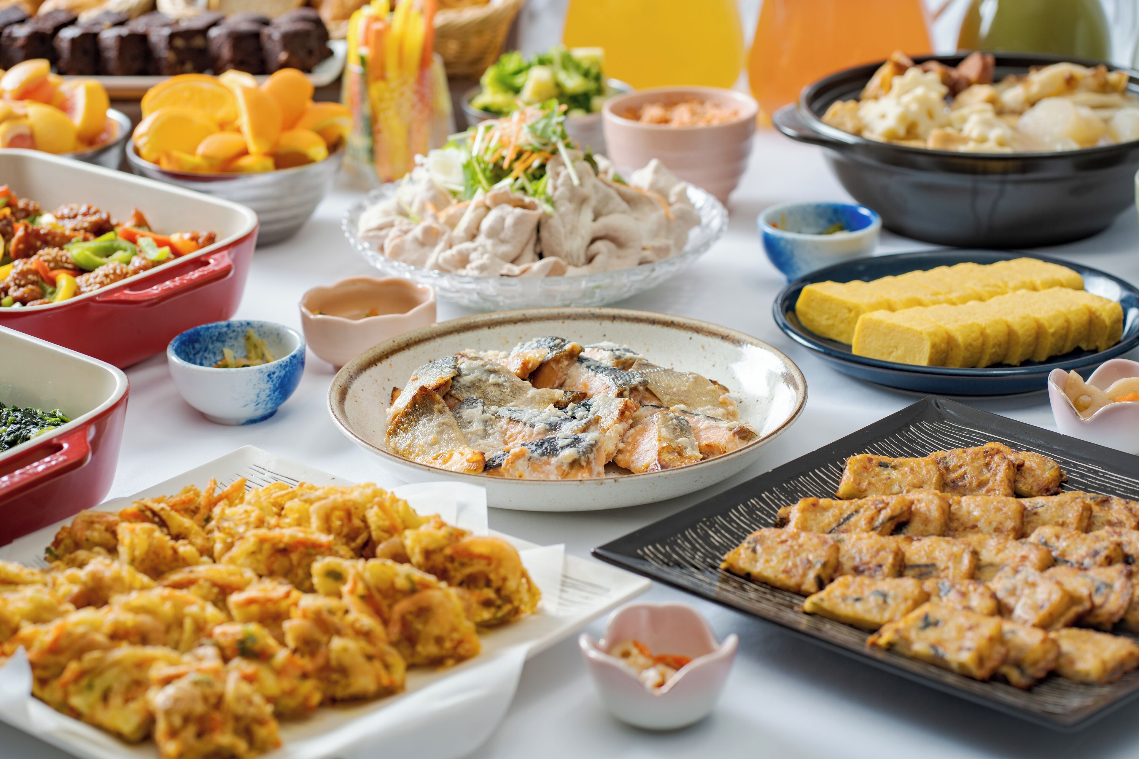 Uma mesa com diversos pratos, incluindo frutos do mar, saladas e sobremesas.
