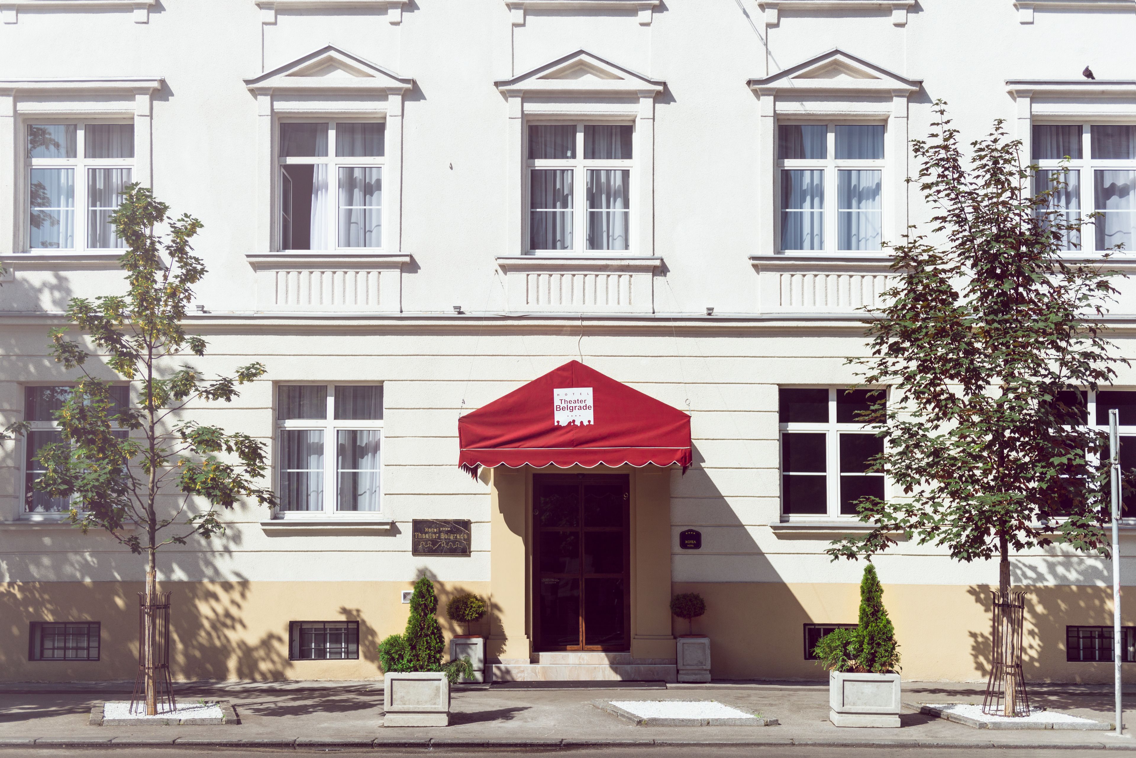 Um edifício com toldo vermelho e uma placa que diz 'Theater Belgrade'.