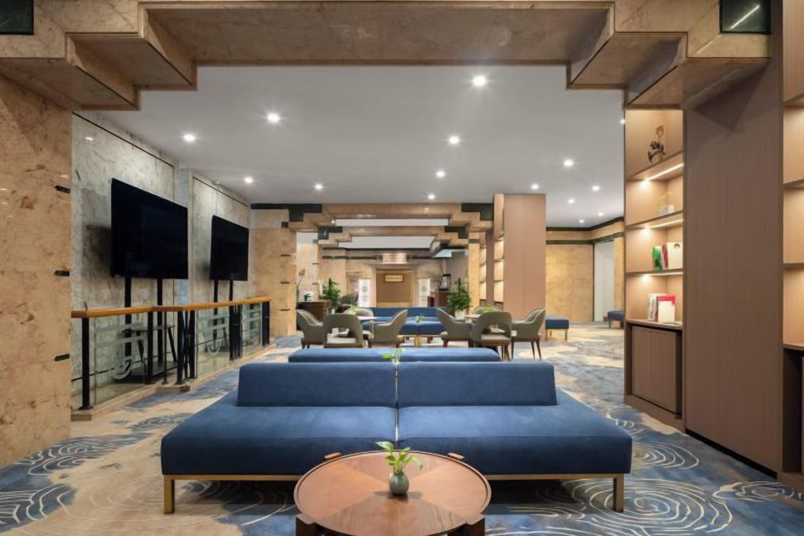 Um saguão de hotel com sofás, uma mesa de centro e uma televisão.