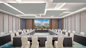 Sala de conferências com uma mesa comprida, cadeiras e vista para a cidade.