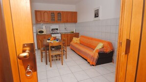 Cozinha compacta com armários de madeira, uma mesa de jantar com cadeiras e um sofá.