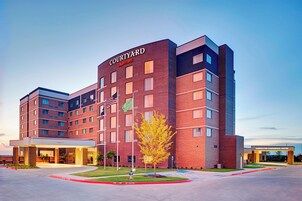 Um hotel Courtyard Marriott com fachada de tijolos, vários andares e entrada central.