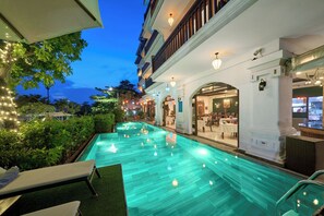 Uma área de piscina com espreguiçadeiras, um espaço de estar coberto e um restaurante com mesas ao ar livre.