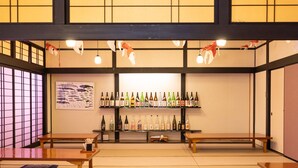 Um quarto japonês tradicional com tatames, mesas de madeira e uma parede de garrafas de saquê.