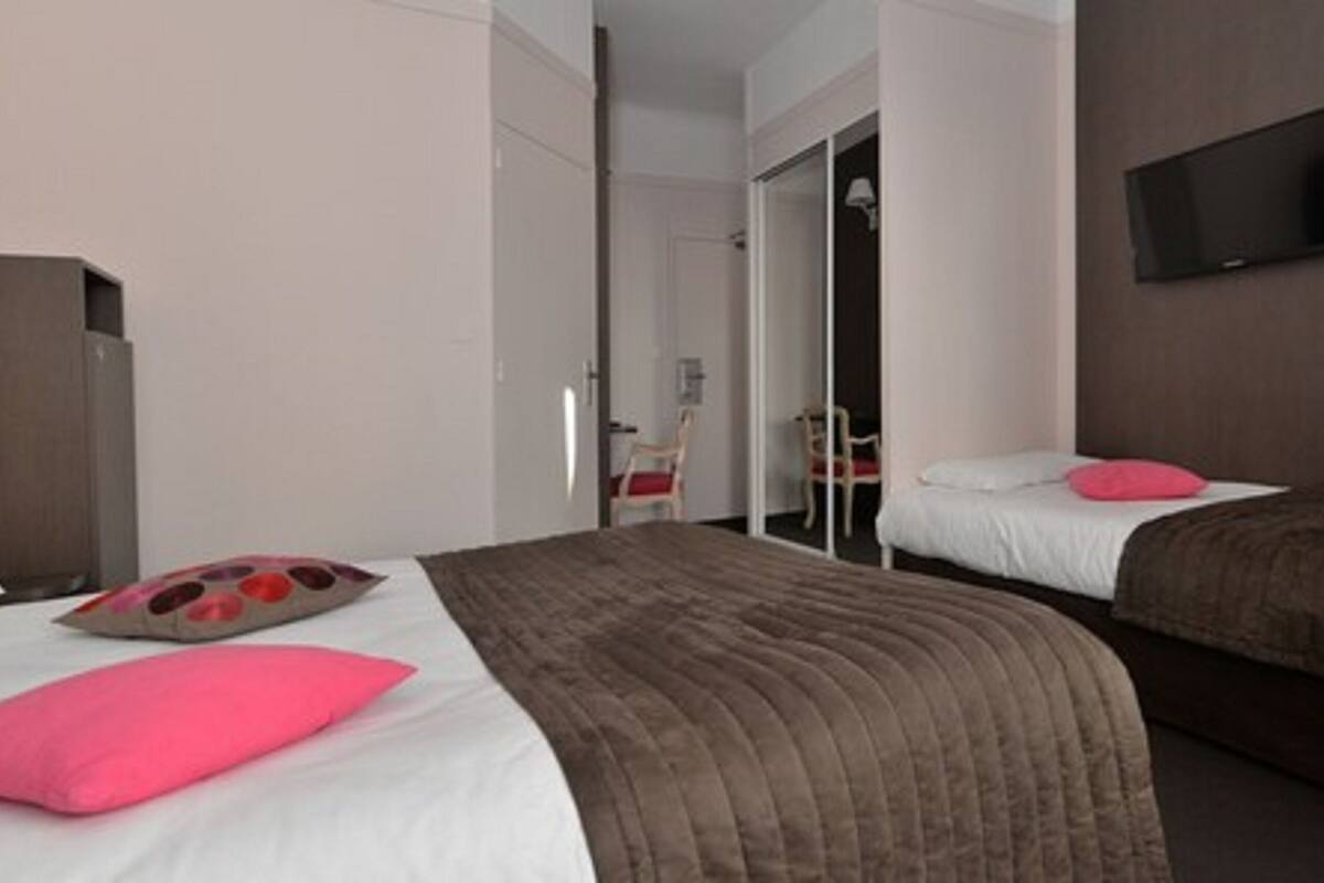 Quarto de hotel com uma cama grande, televisão na parede e porta para o banheiro.
