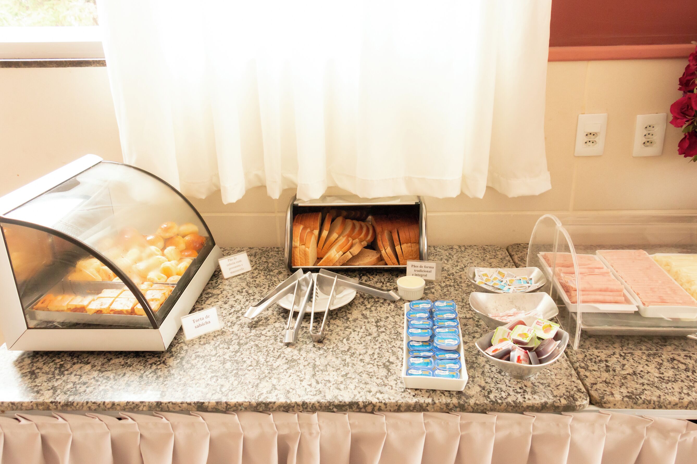 Um buffet de café da manhã com diversos alimentos e utensílios.