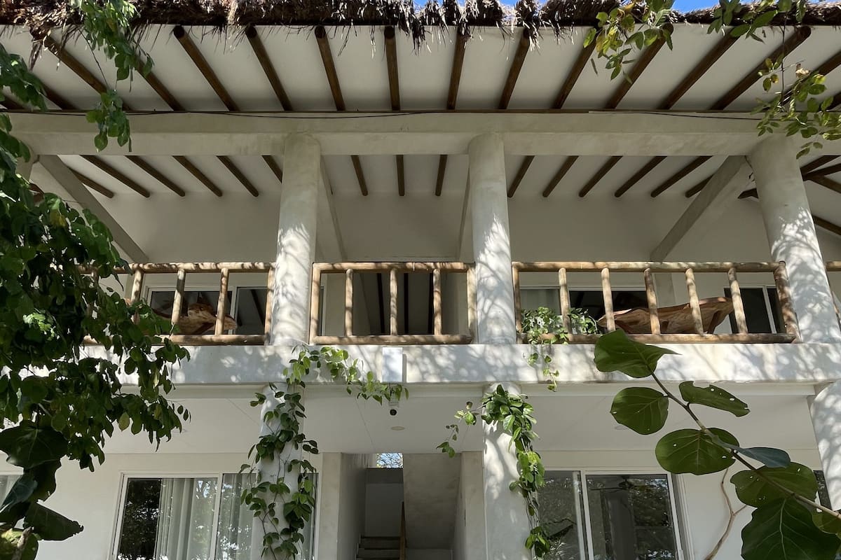 Um edifício de dois andares com entrada coberta, janelas amplas e escadaria que leva ao andar superior.