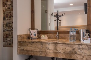 Um banheiro com bancada de mármore, pia, espelho e porta-roupas.
